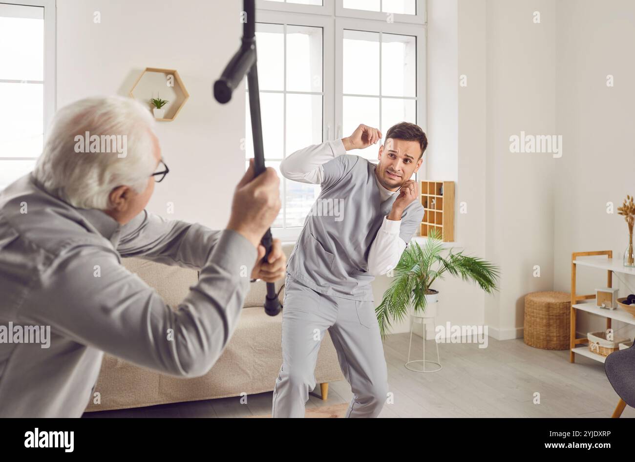 Aggressive old male patient attacking young nurse man with walking ...