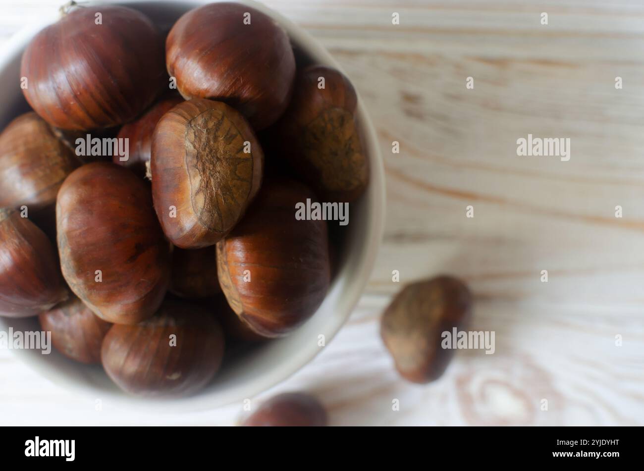 Edible raw chestnuts in a ceramic bowl on the wodden table. The concept ...