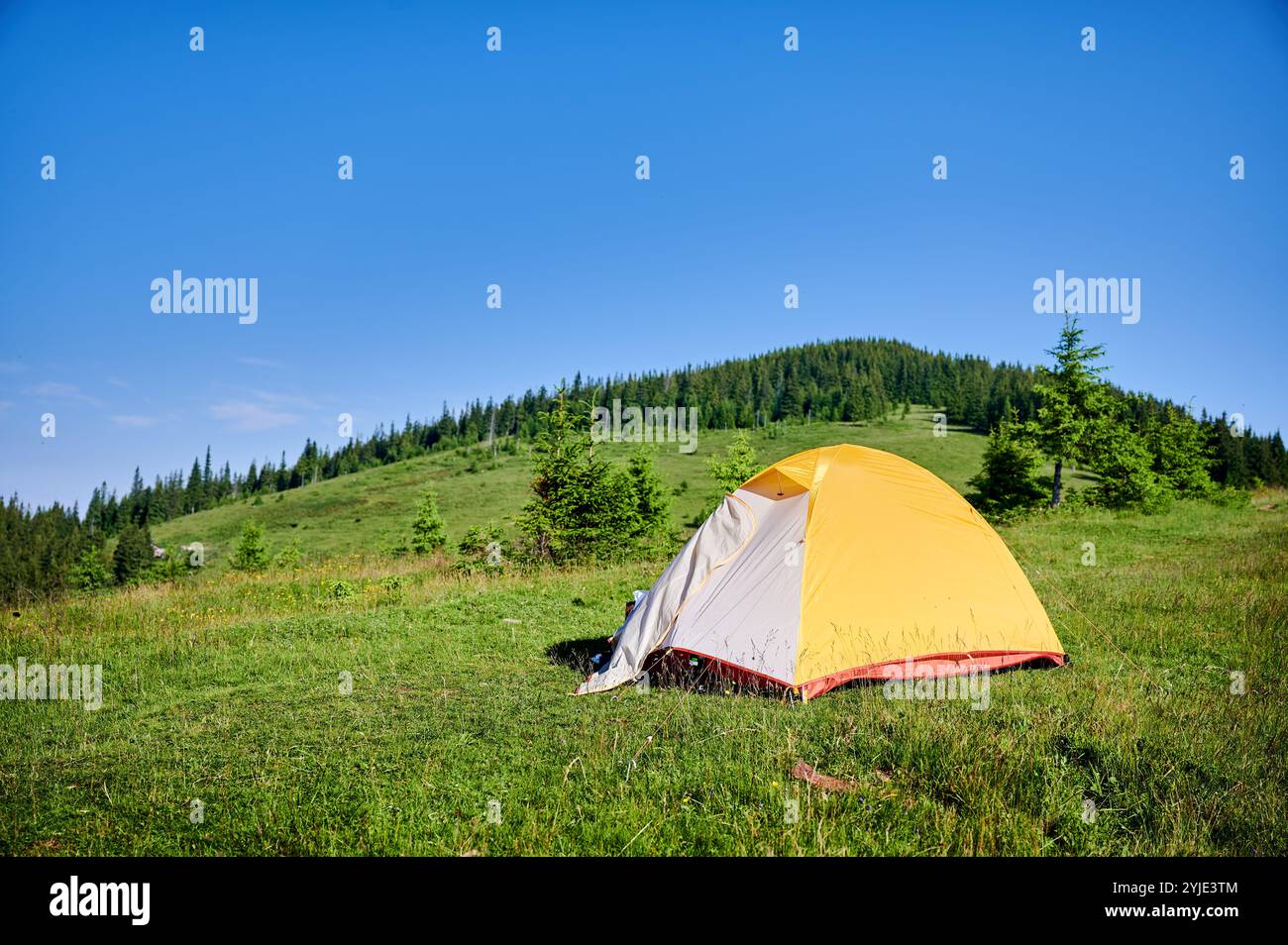 Bright yellow tent on grassy hillside, overlooking breathtaking ...