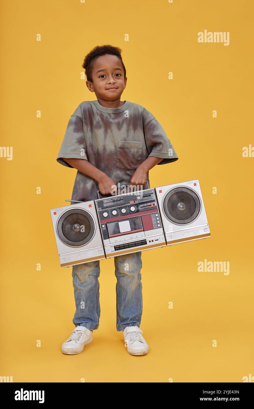 Vertical shot of cute little Black boy smiling at camera holding large ...
