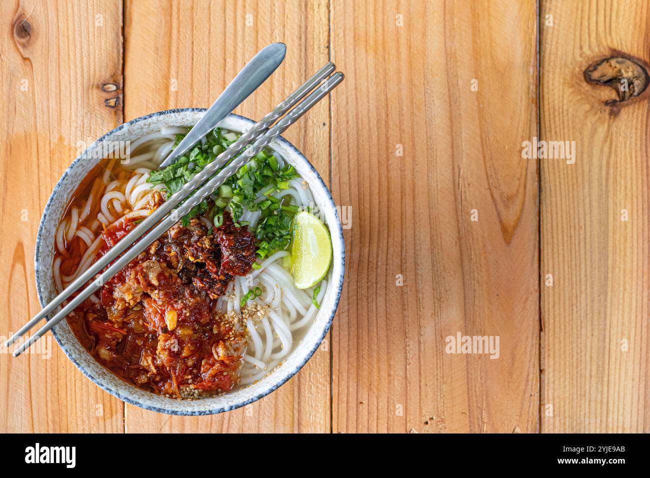 Khao Soi Chiang Tung is served in a bowl with sticky rice noodles and a ...