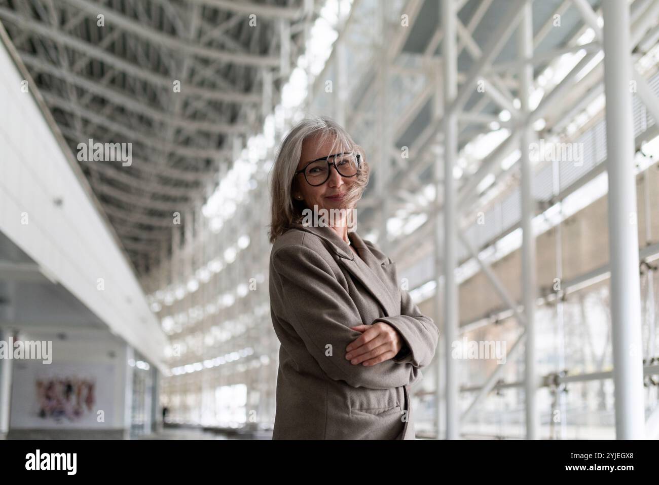 Older woman smiling confidently in a modern building with large windows ...