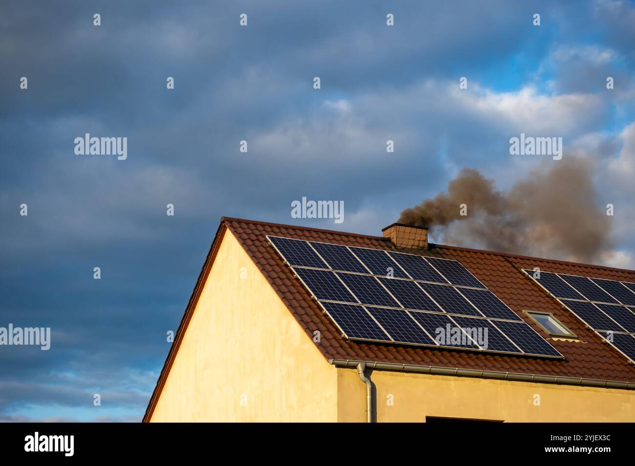 Black smoke from the chimney of a single-family home. Roof covered with ...