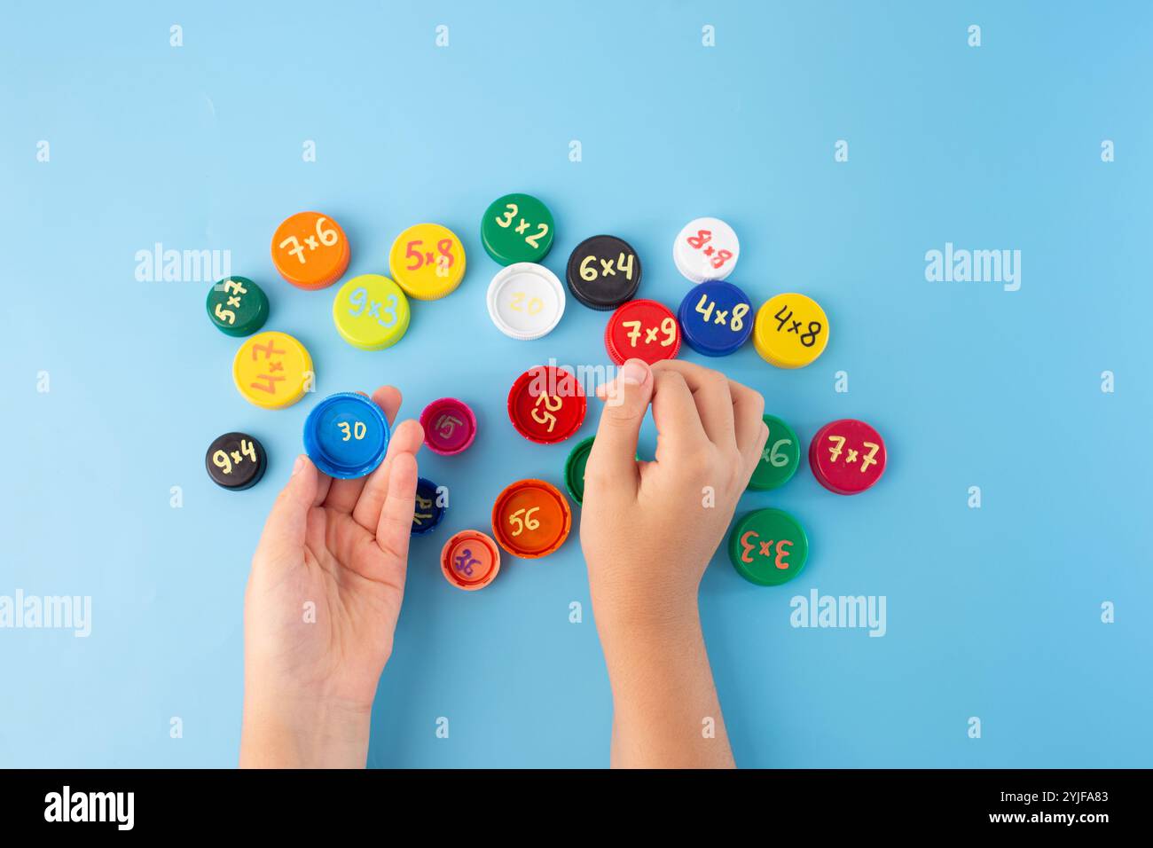 Childrens hands placing colorful caps with multiplication problems on ...