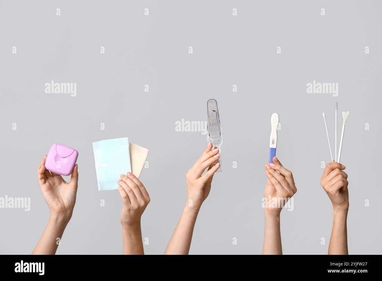 Hands with menstrual pads, pregnancy test and pap test tools on grey ...