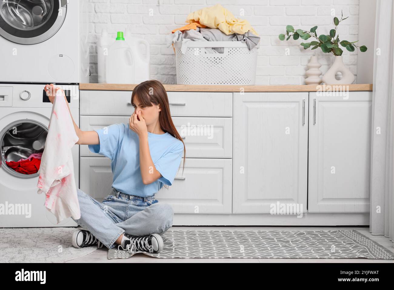 Disgusted young woman with smelly clothes in laundry room Stock Photo ...