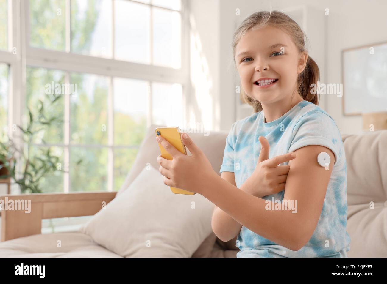 Diabetic girl with glucose sensor using mobile phone for measuring ...