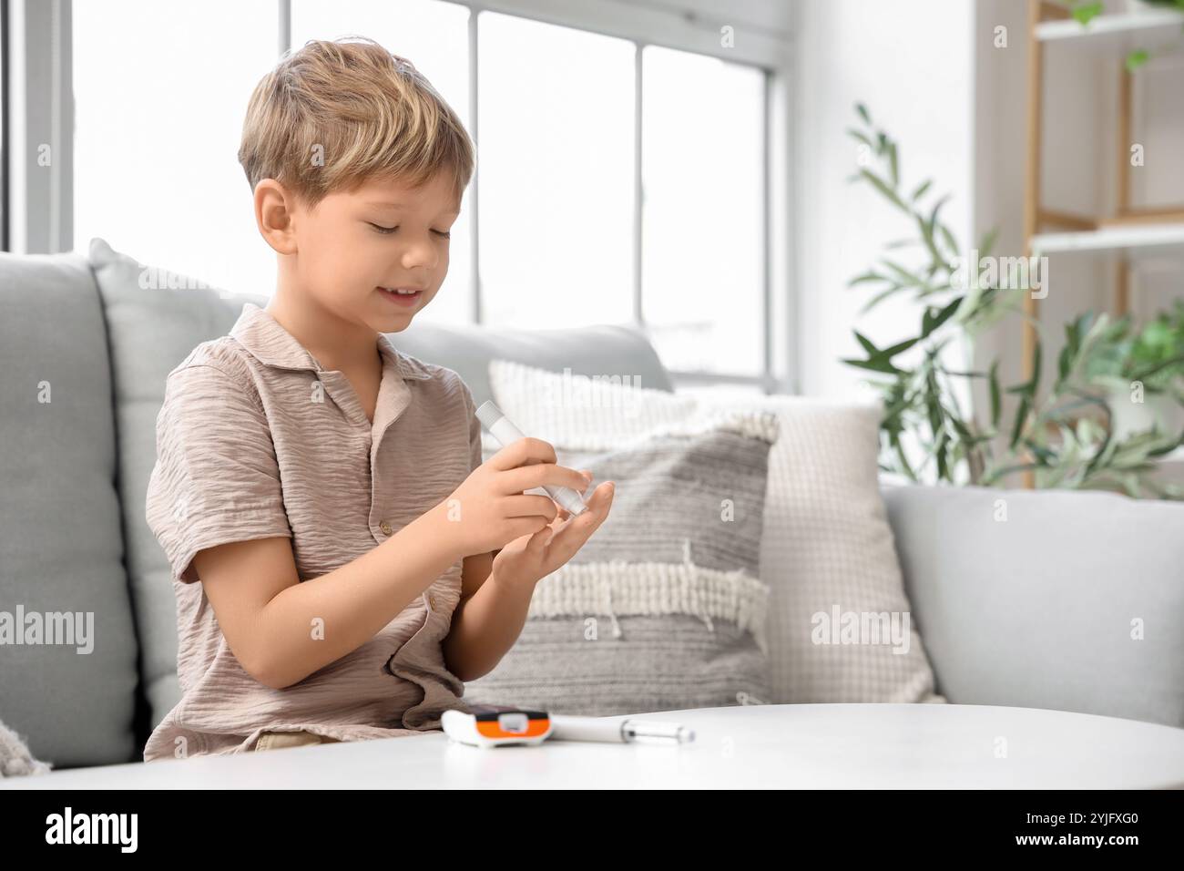 Little diabetic boy using lancet pen on sofa at home Stock Photo - Alamy