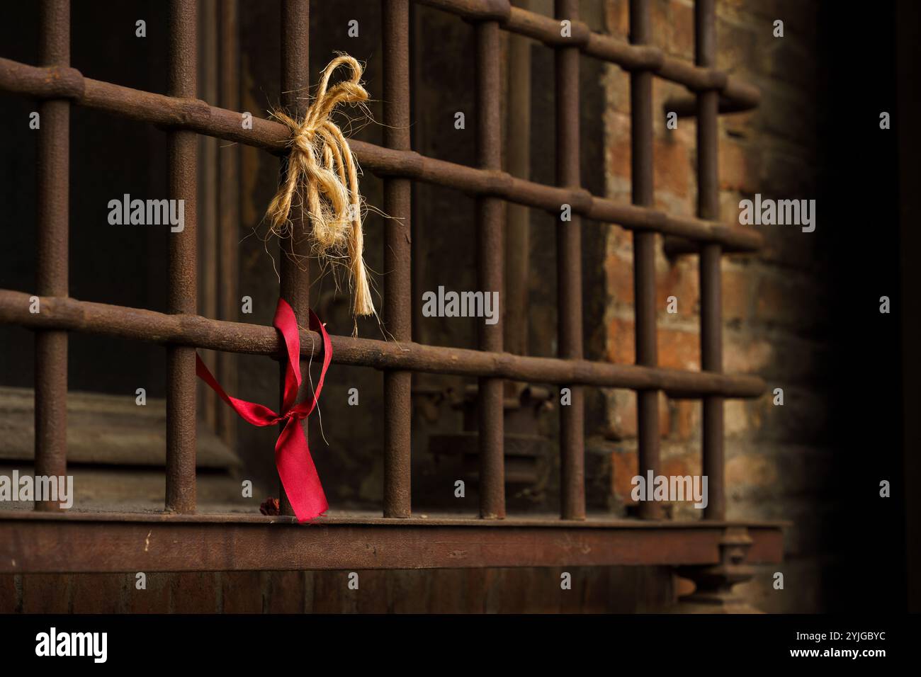 A red ribbon and a piece of rope tied to rusty bars Stock Photo - Alamy