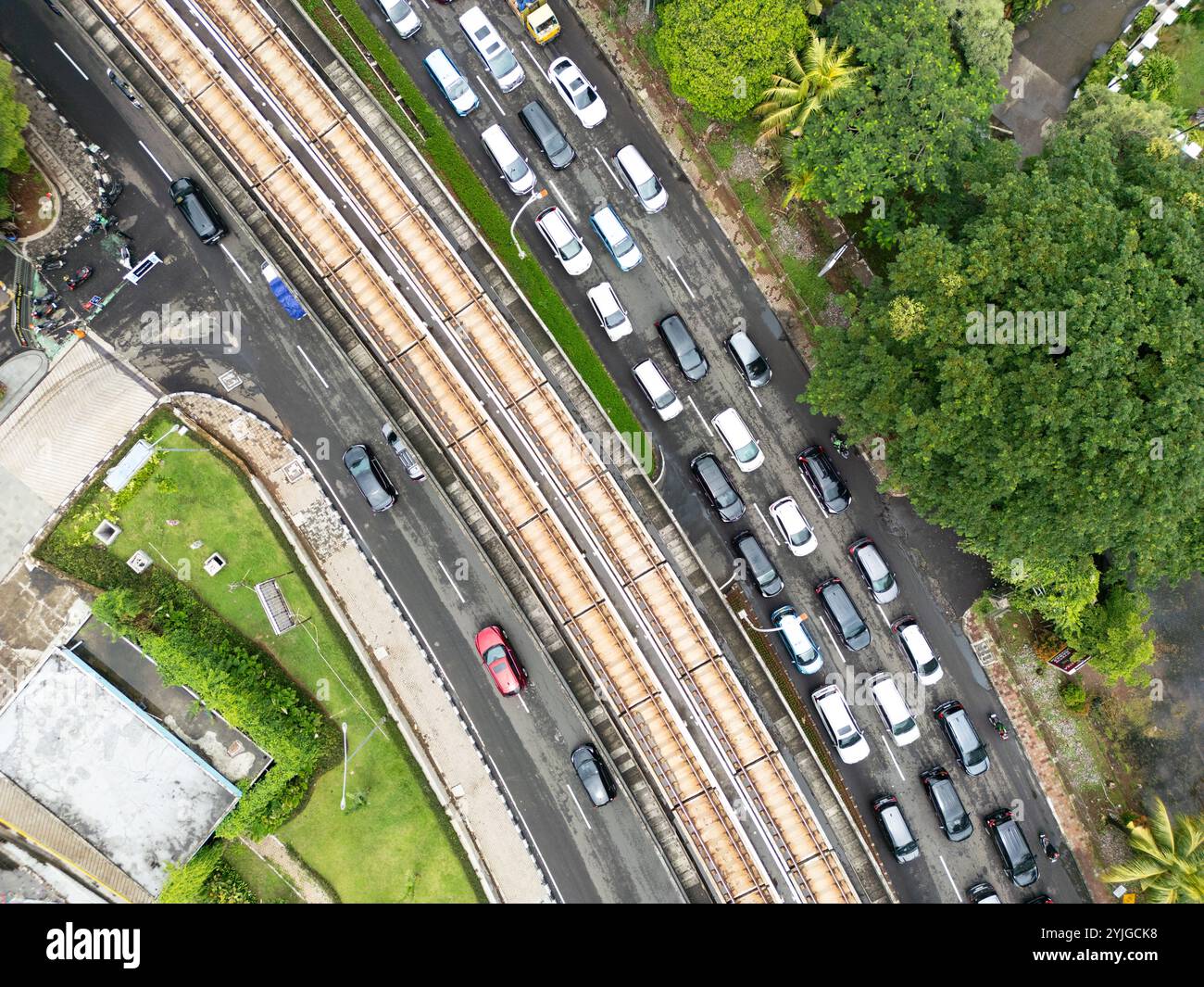 Overhead view of a busy road in Jakarta with an elevated train track running alongside, urban ...
