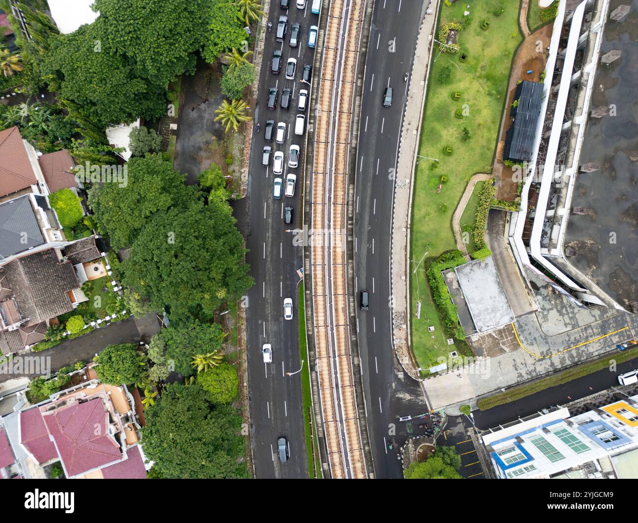 Overhead view of a busy road in Jakarta with an elevated train track running alongside, urban ...