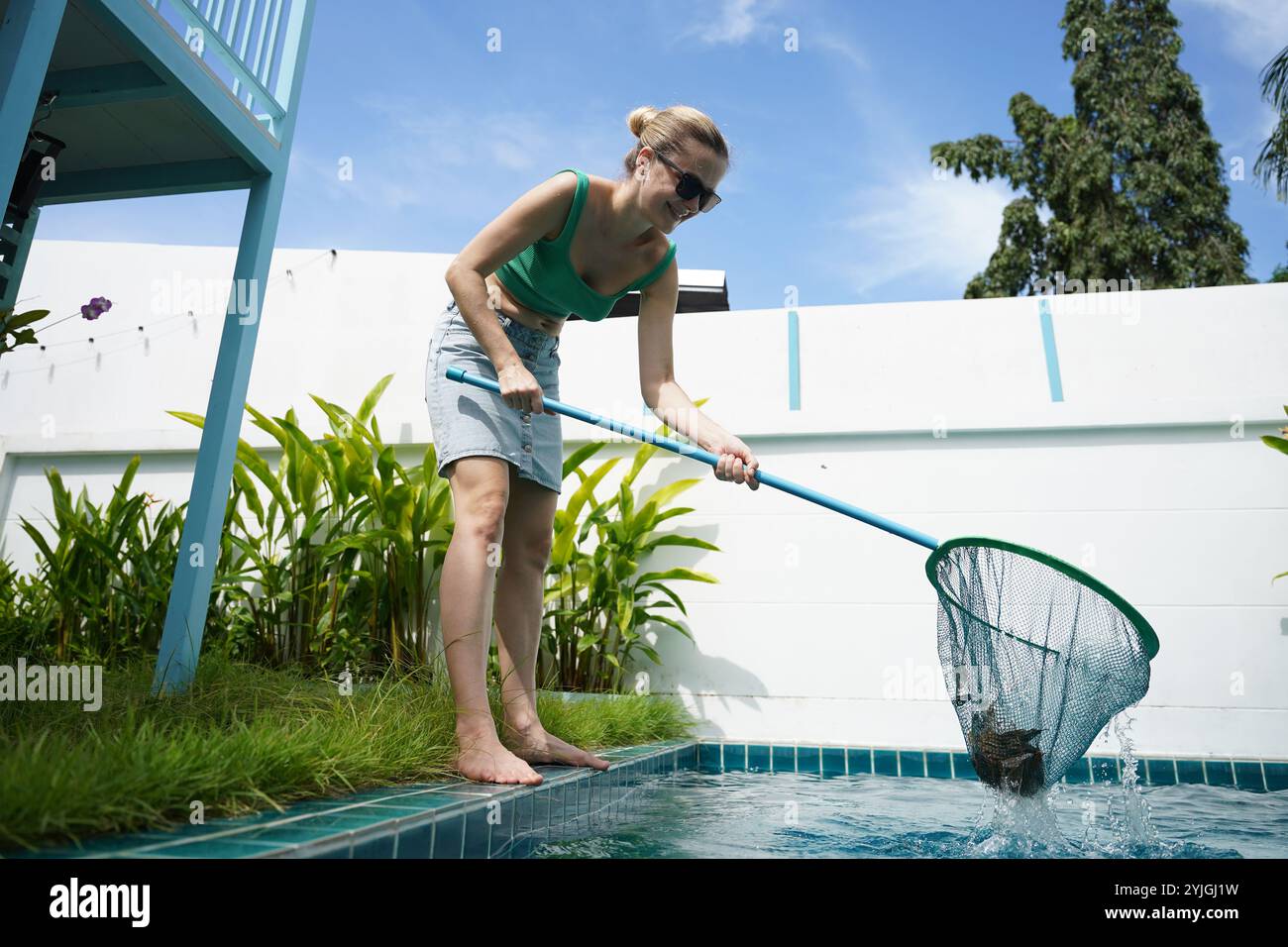 A young woman clean leaves out of a pool Stock Photo - Alamy