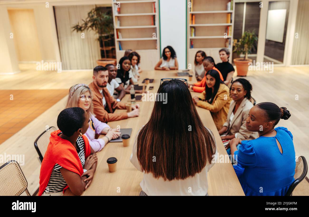 A businesswoman leads a dynamic discussion with a diverse group of ...