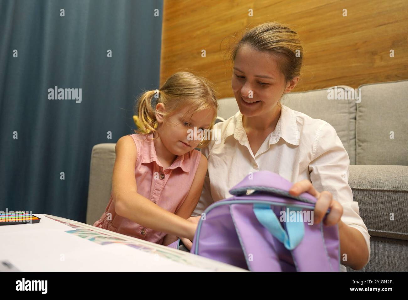 Mother helps her daughter pack her backpack Stock Photo - Alamy