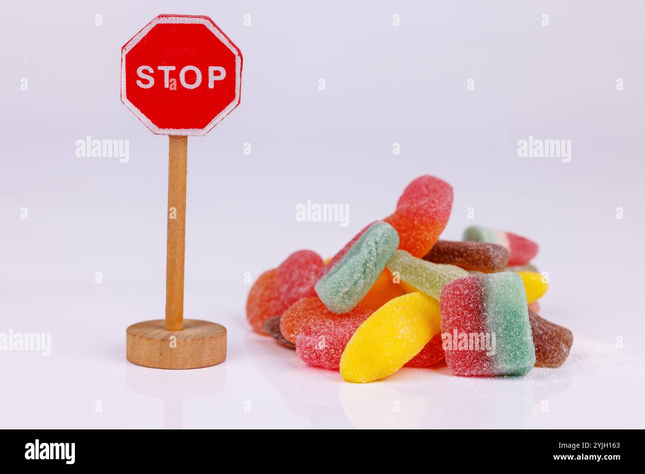A wooden stop sign with a mountain of vibrant gummy candies in the ...
