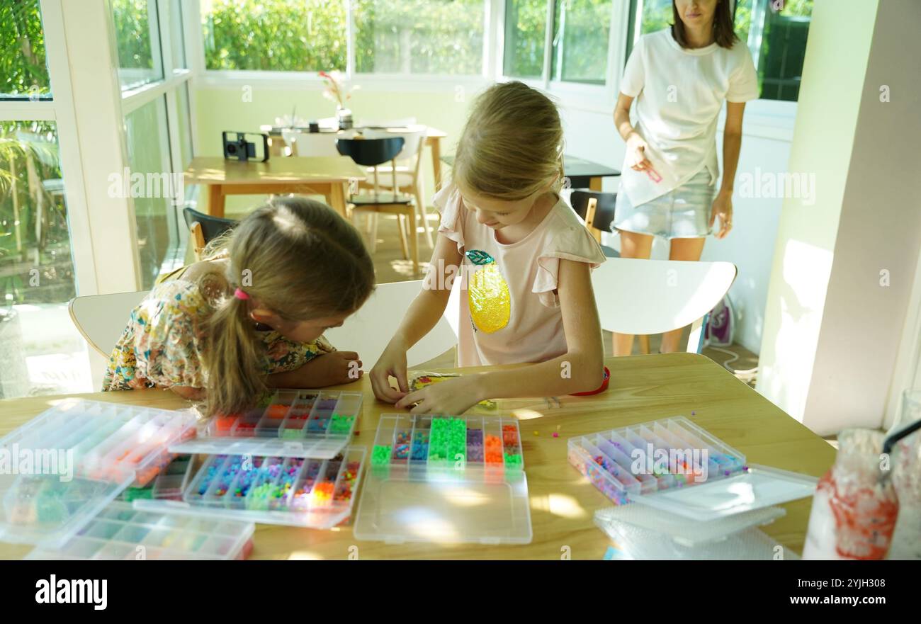 Teacher in workshop teched two girls how to assemble a thermo mosaic ...