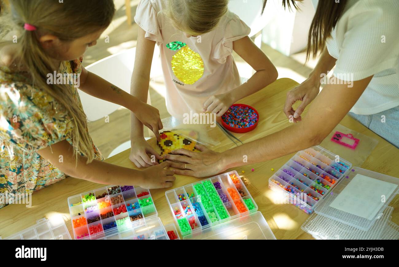 Teacher in workshop teched two girls how to assemble a thermo mosaic ...