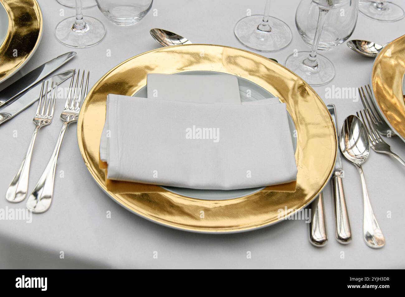 Luxurious table setting featuring gold charger plates, silverware, and ...