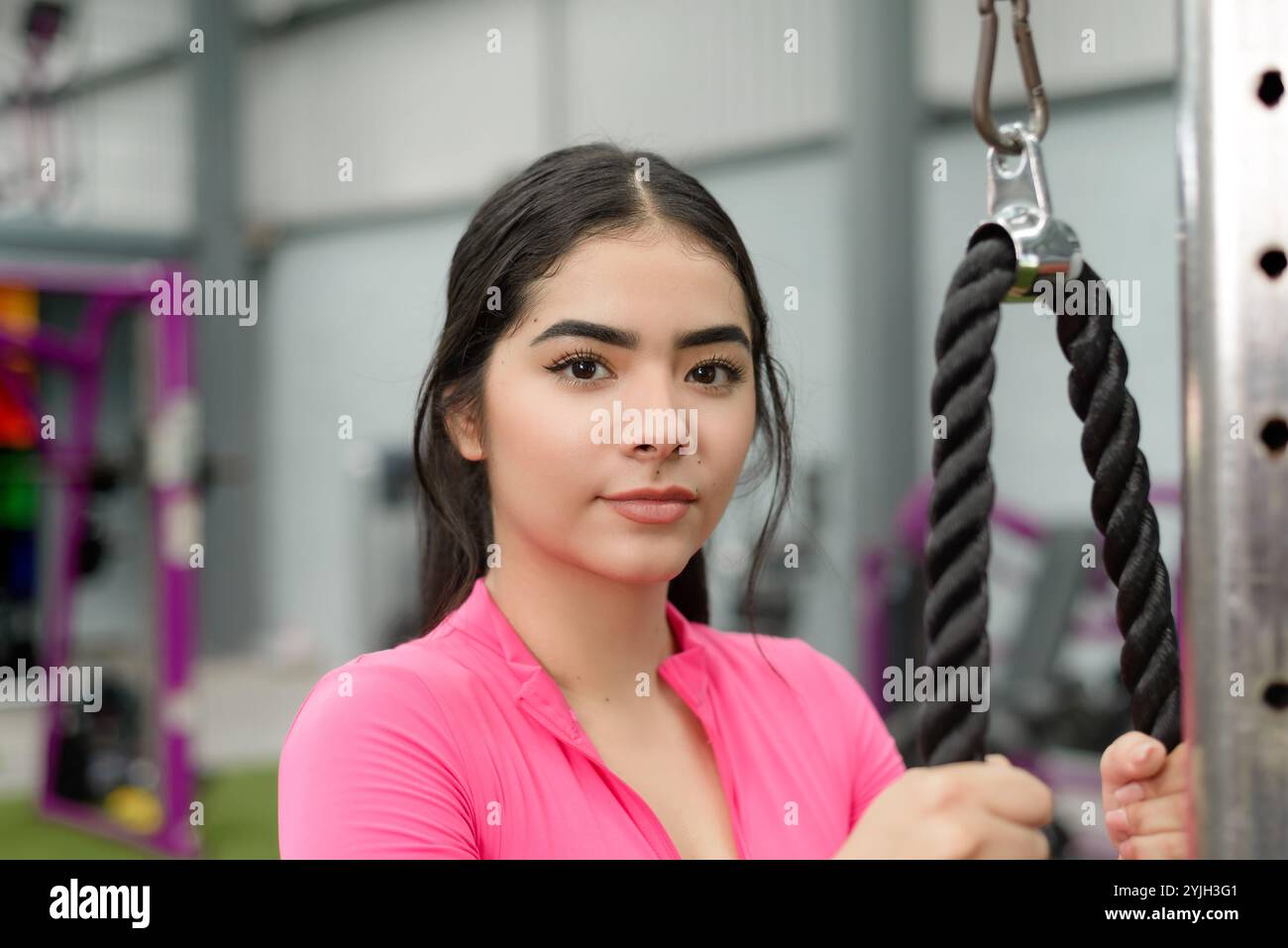 Woman doing cable arm exercises at the gym, using the rope attachment ...