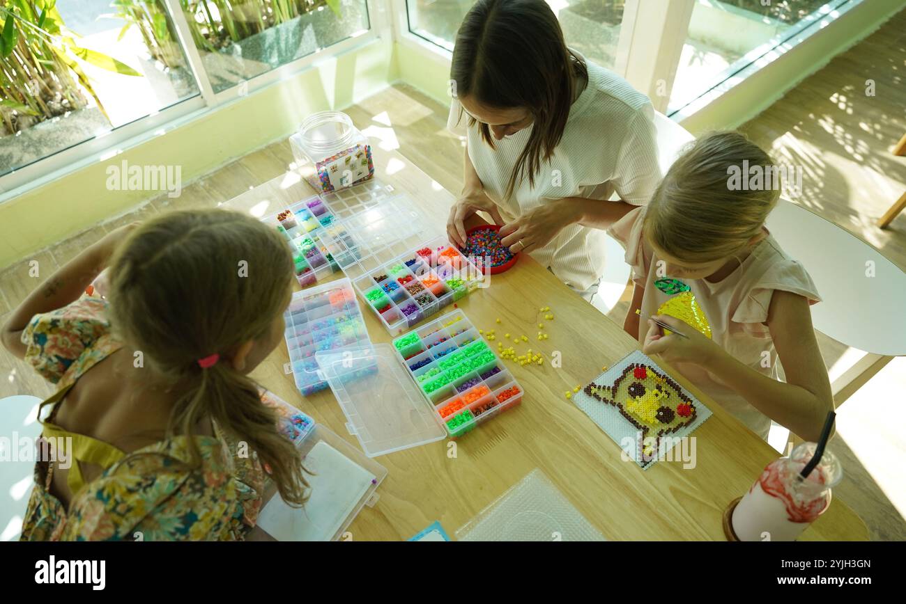 Teacher in workshop teched two girls how to assemble a thermo mosaic ...