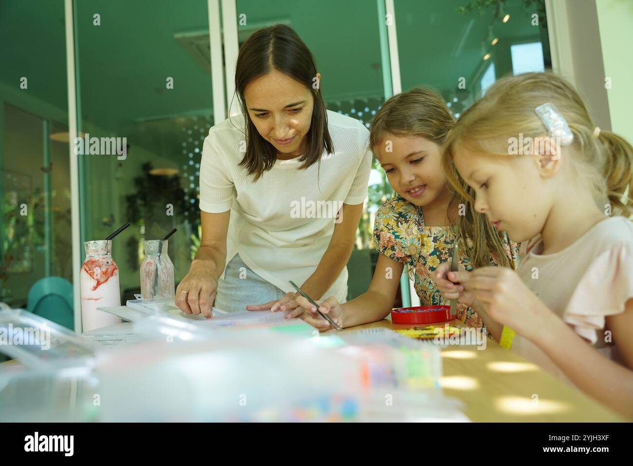 Teacher in workshop teched two girls how to assemble a thermo mosaic ...