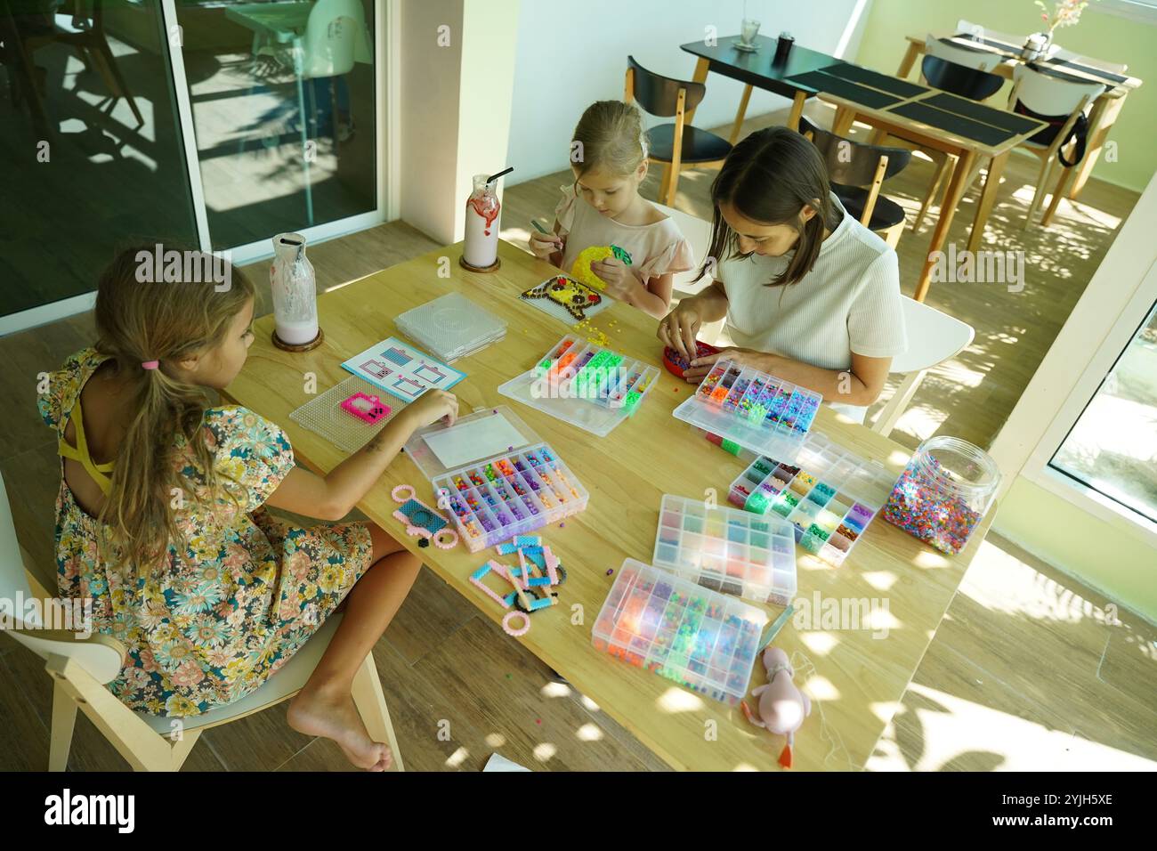Teacher in workshop teched two girls how to assemble a thermo mosaic ...