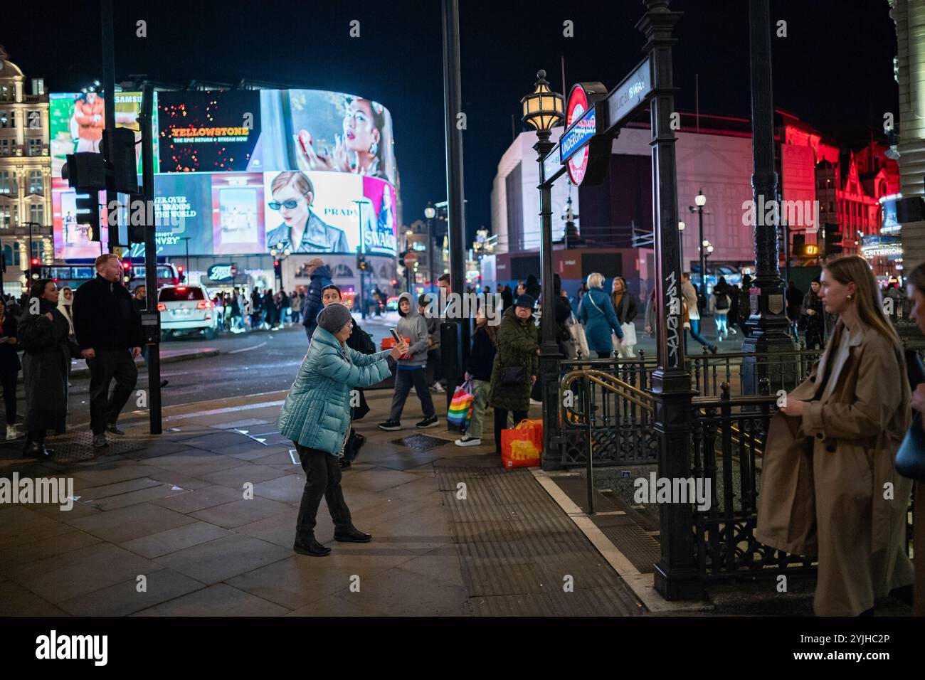 London winter tourist taking photographs in the Capital outside the entrance of Piccadilly ...