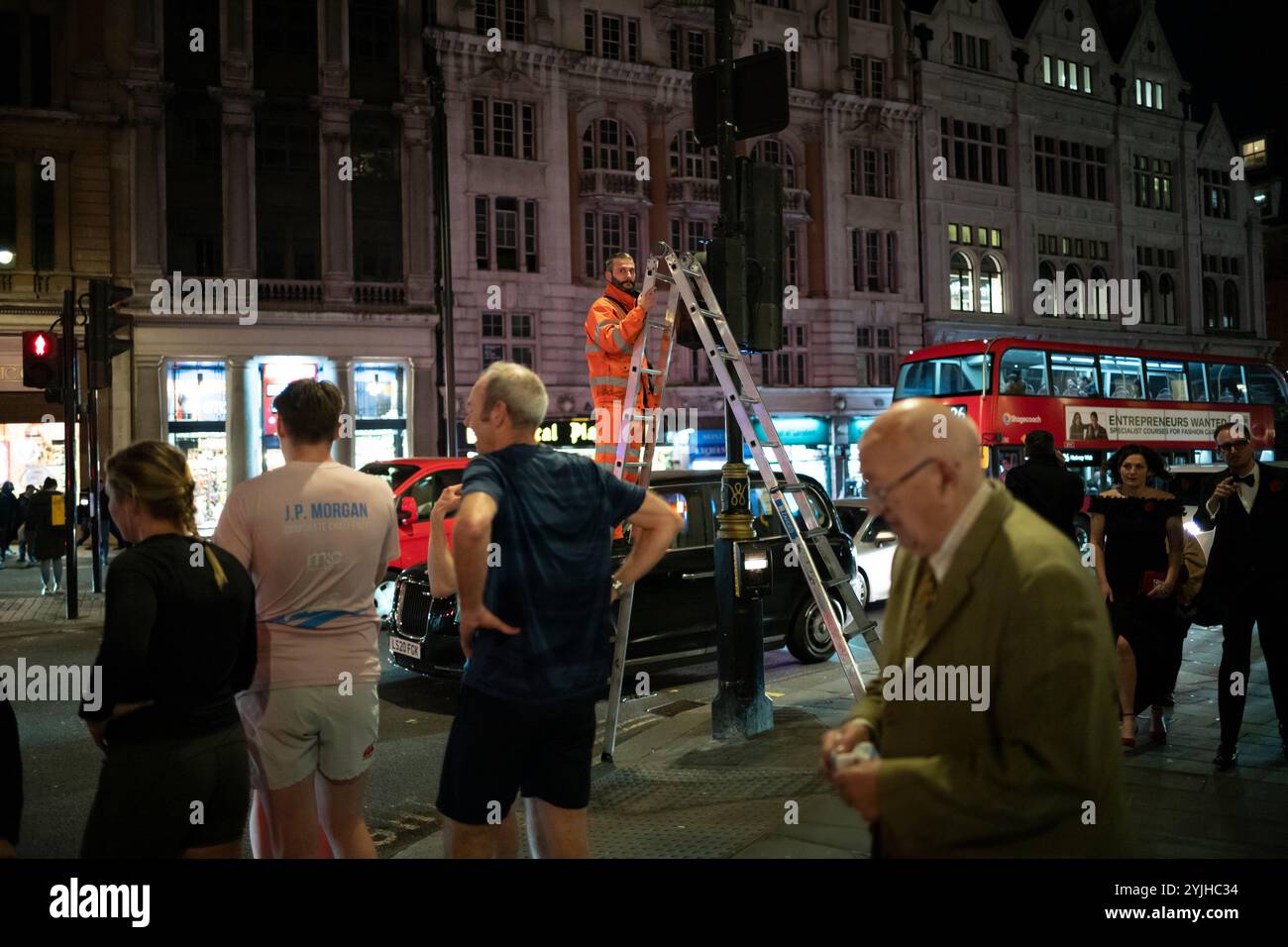A workman oh his step ladder fixing a traffic light during the winter ...