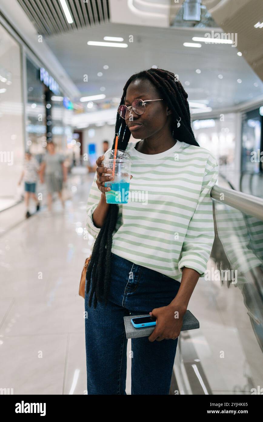 Young woman is enjoying a refreshing beverage while navigating a ...