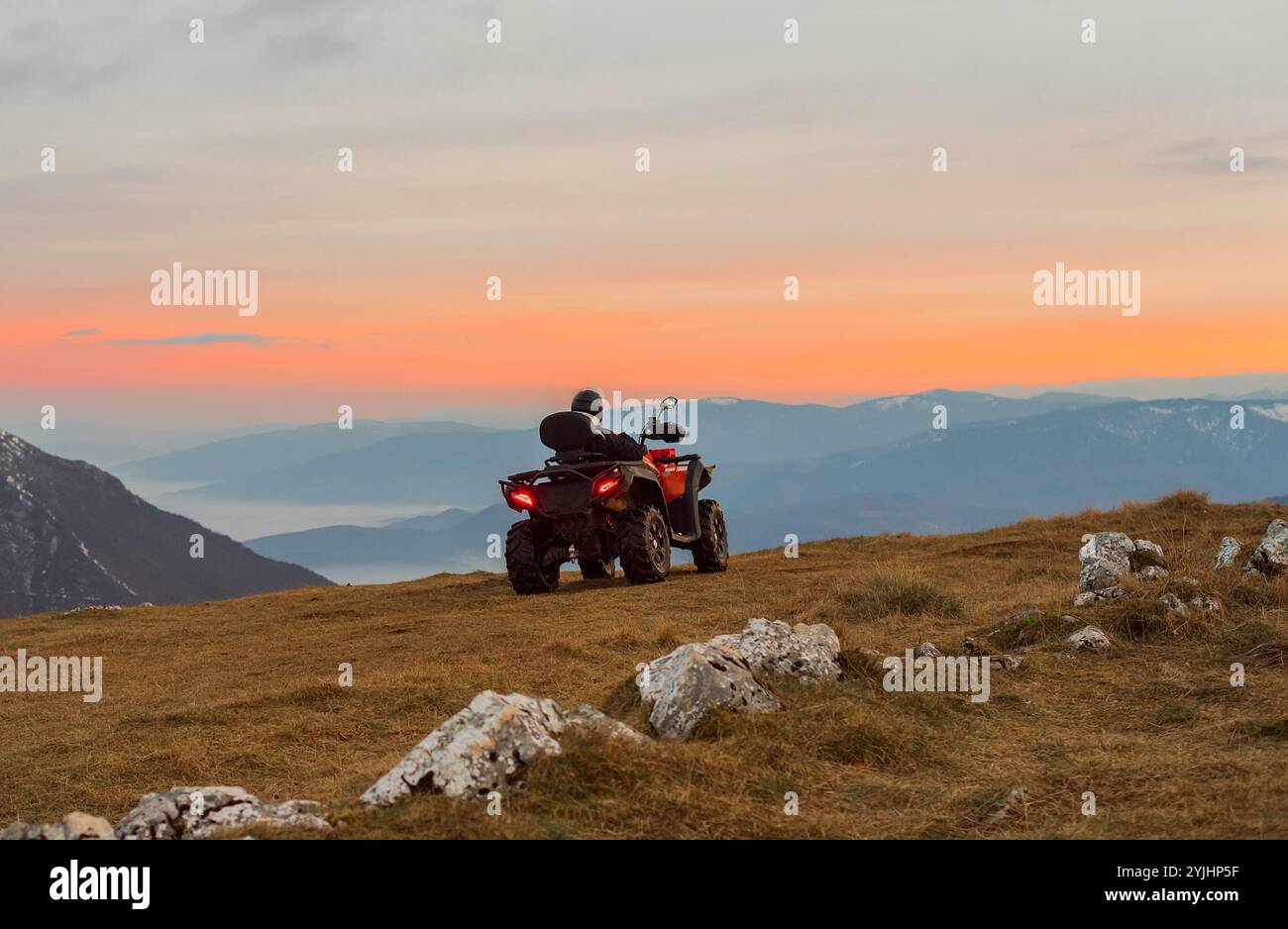 A rider riding quad bike atv off road on the mountain at sunset ...