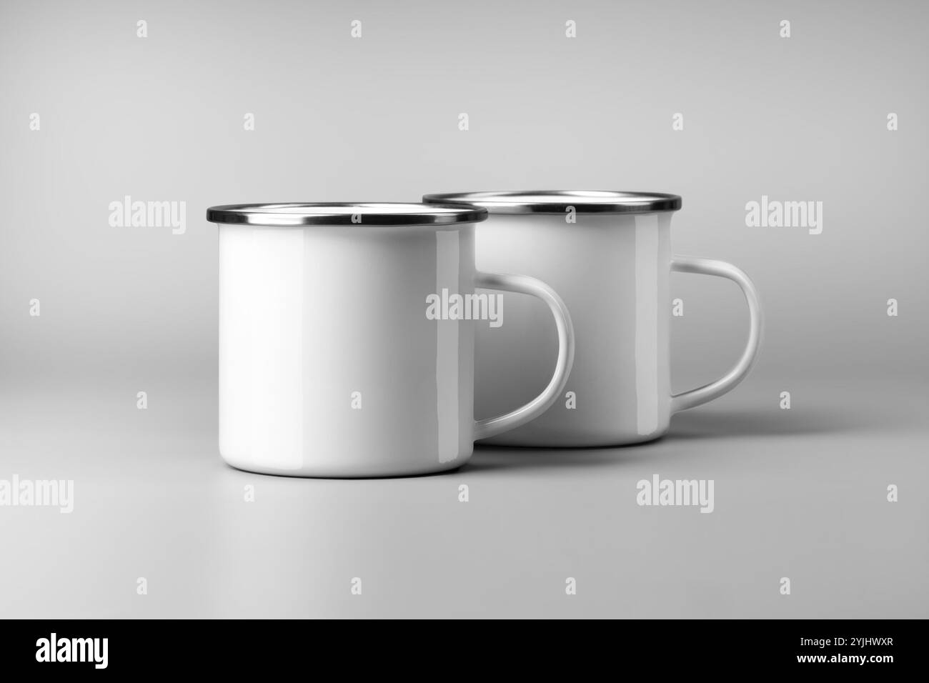 Mockup of two white metal cups, enamel mug with mirrored side, handle ...