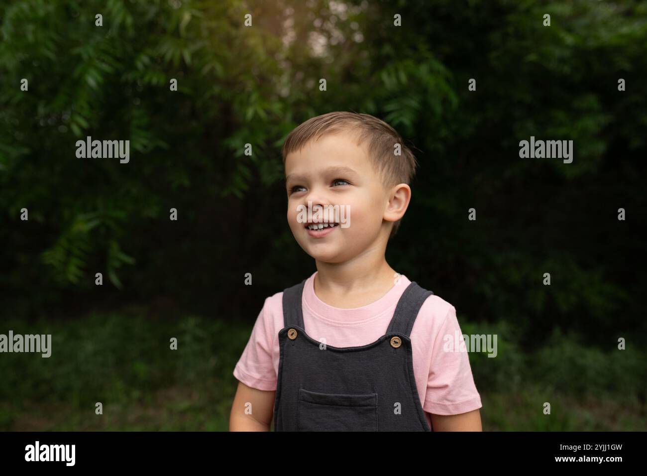 young boy smiling and looking up with forest background Stock Photo - Alamy