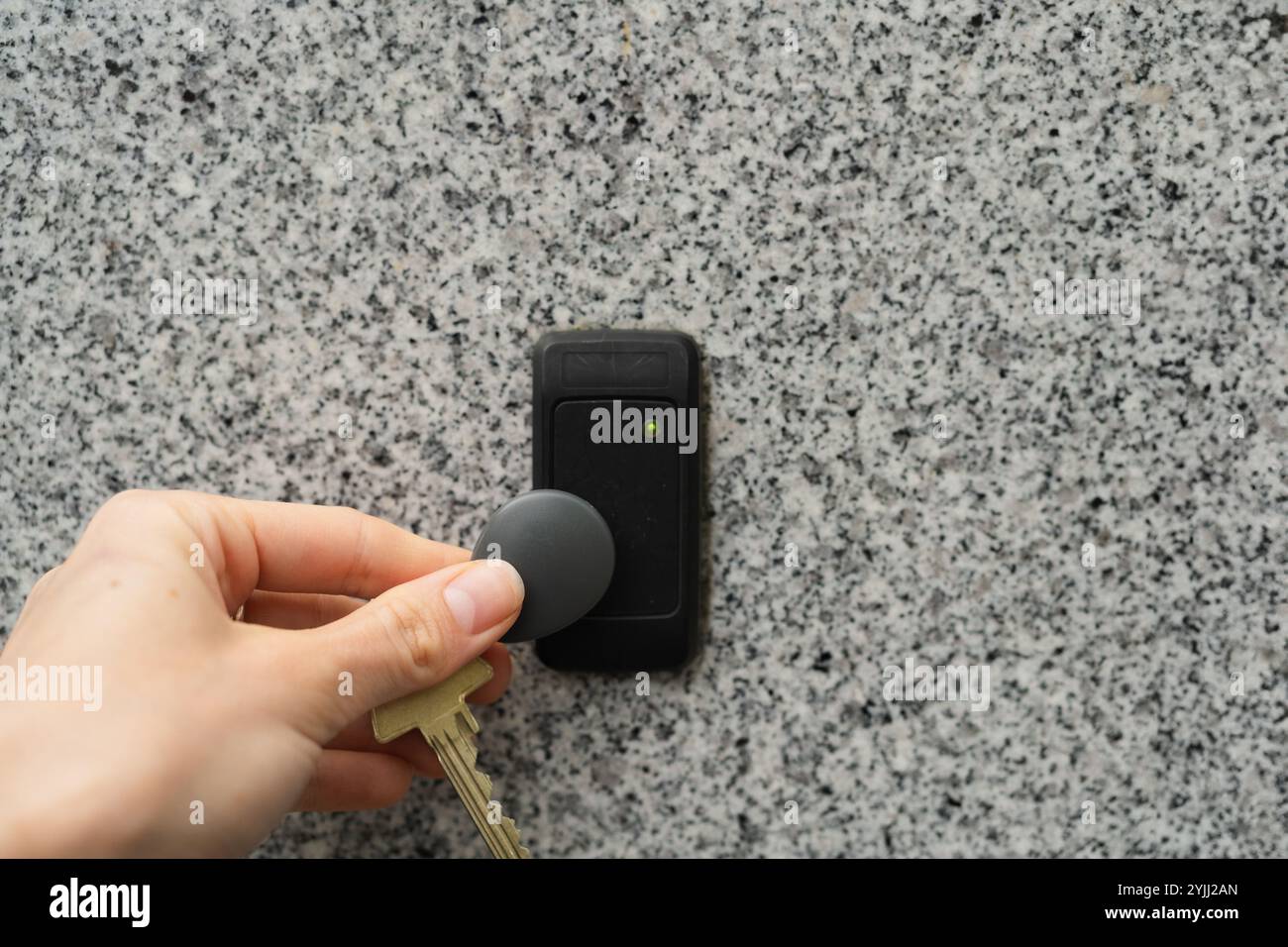 Woman's hand holding key fob next to the door opening device Stock ...
