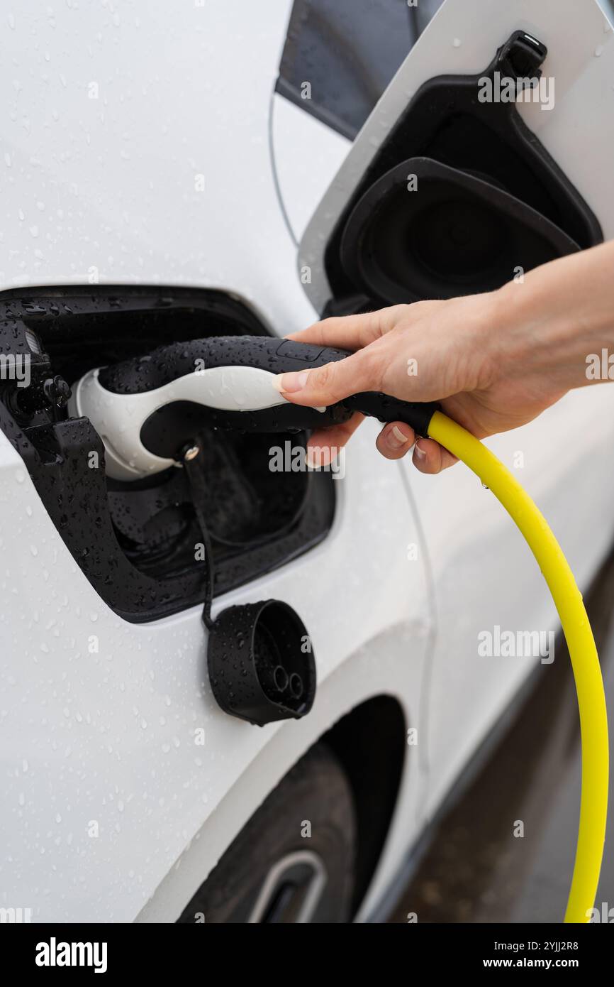 Woman's hand charging white electric car via plug Stock Photo - Alamy