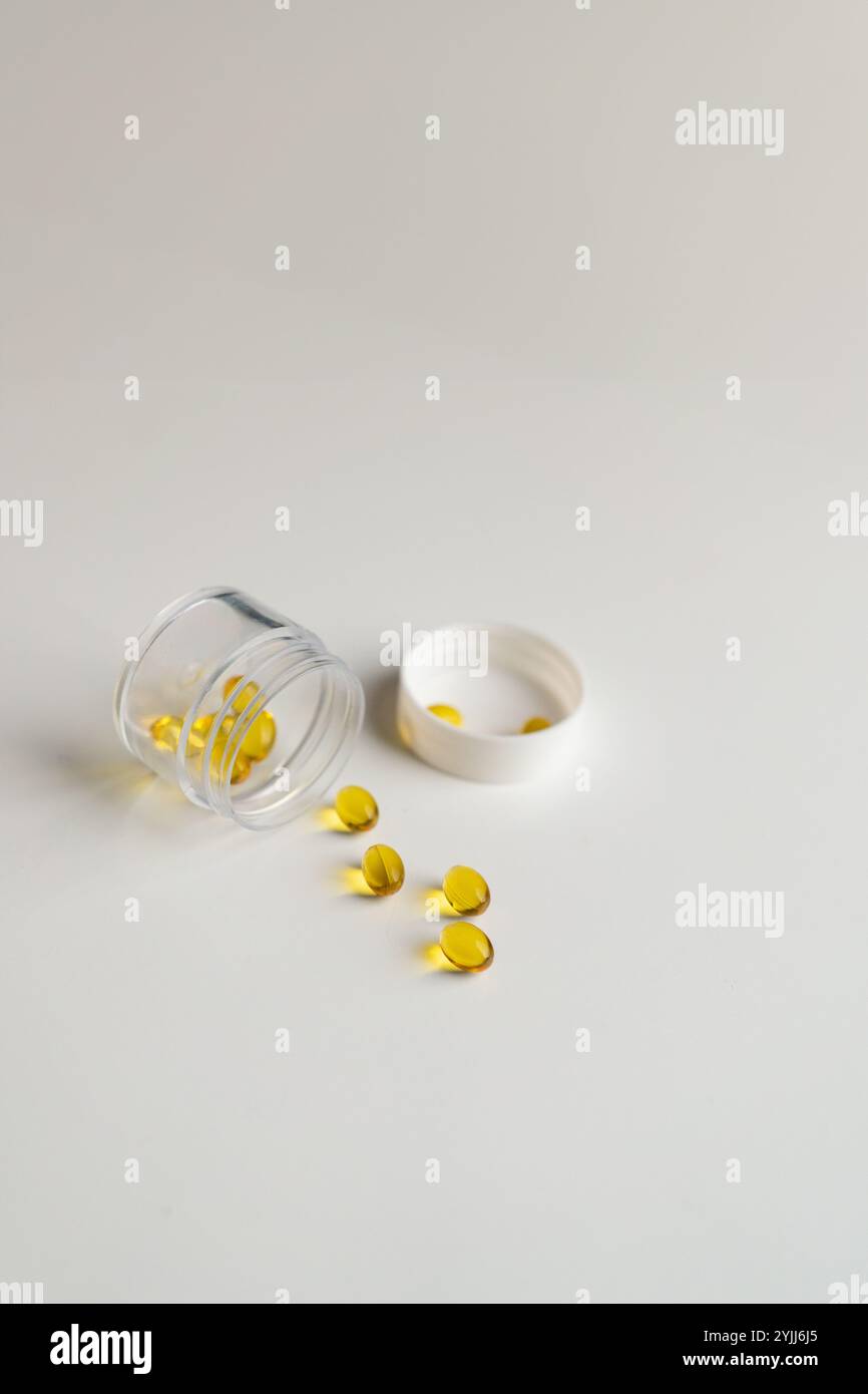 Open bottle of yellow capsule vitamins on white background Stock Photo ...