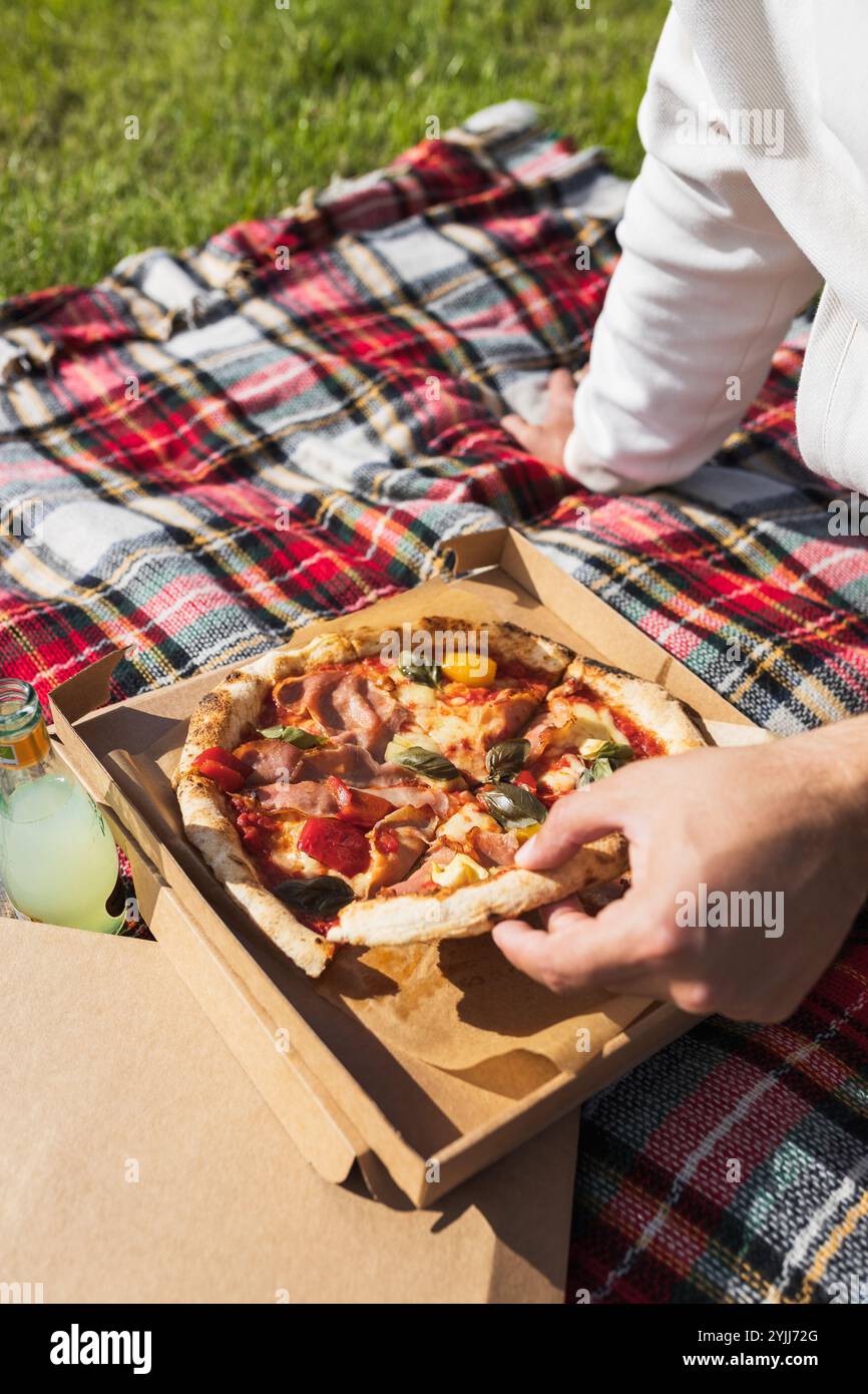 Man's hand with a piece of fresh pizza outside in picnic setting Stock ...