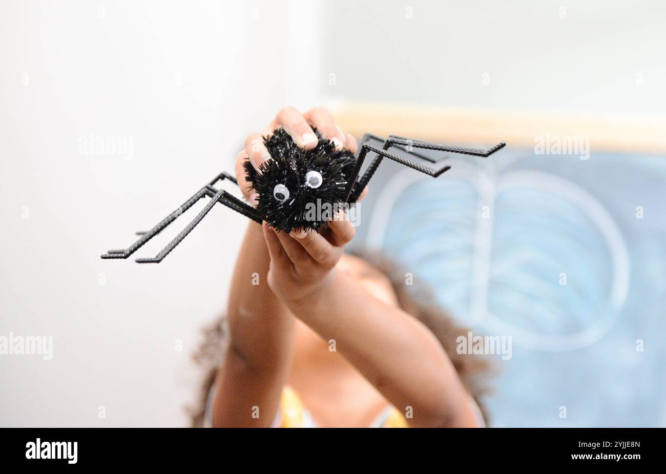 Child holding a handmade black spider with googly eyes and long Stock ...