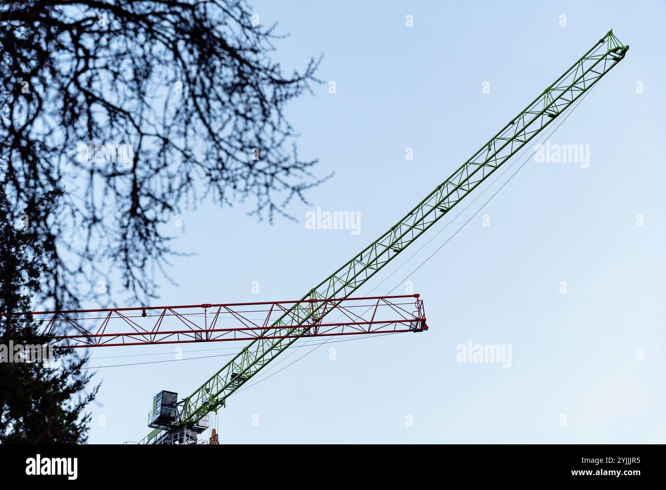 Two arrows of construction cranes, red and green, are photographed from ...