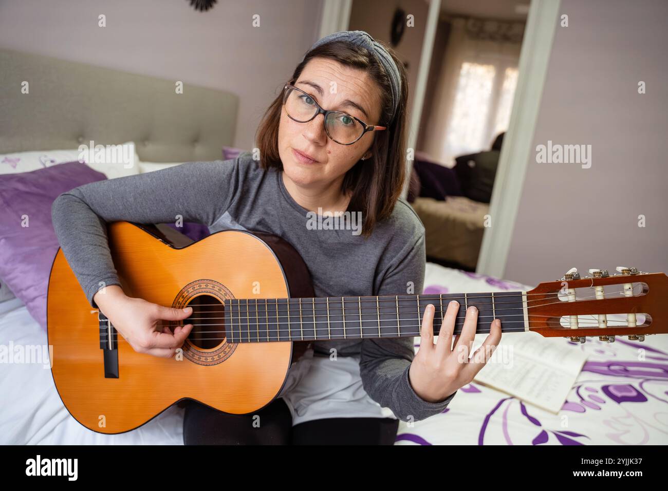 Musician practicing chords on a spanish guitar in the bedroom, sitting ...