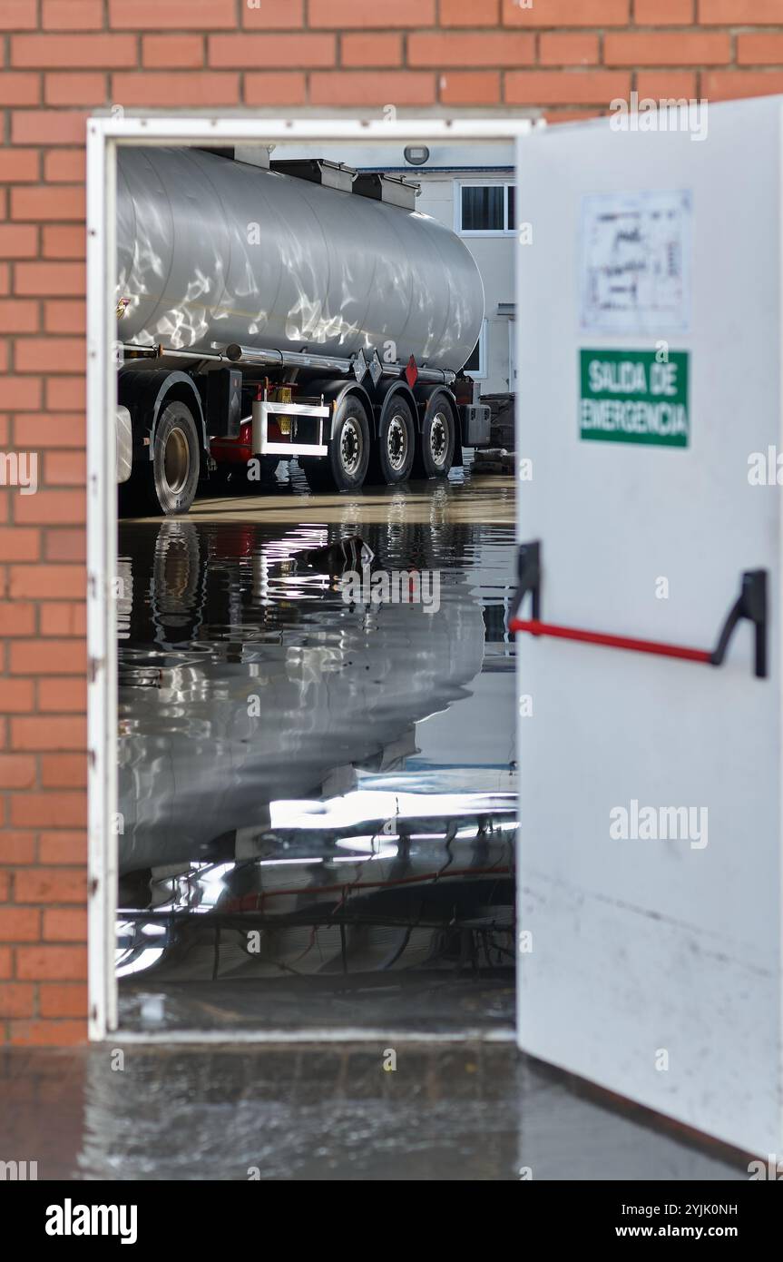 Flooded warehouse with a tanker truck visible through the open door ...