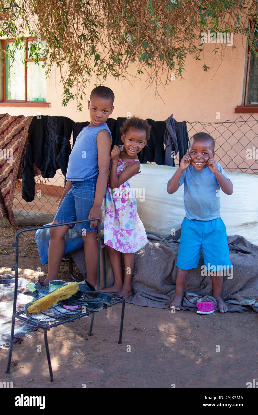 three African children playing in the yard of the house in the village ...