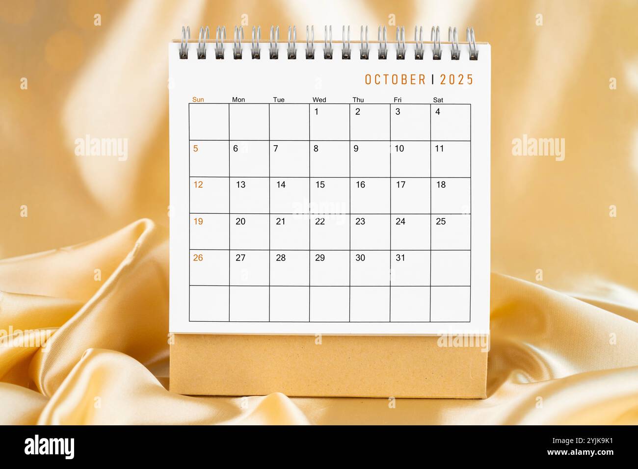 Front view of October 2025 desk calendar on gold silk background Stock ...