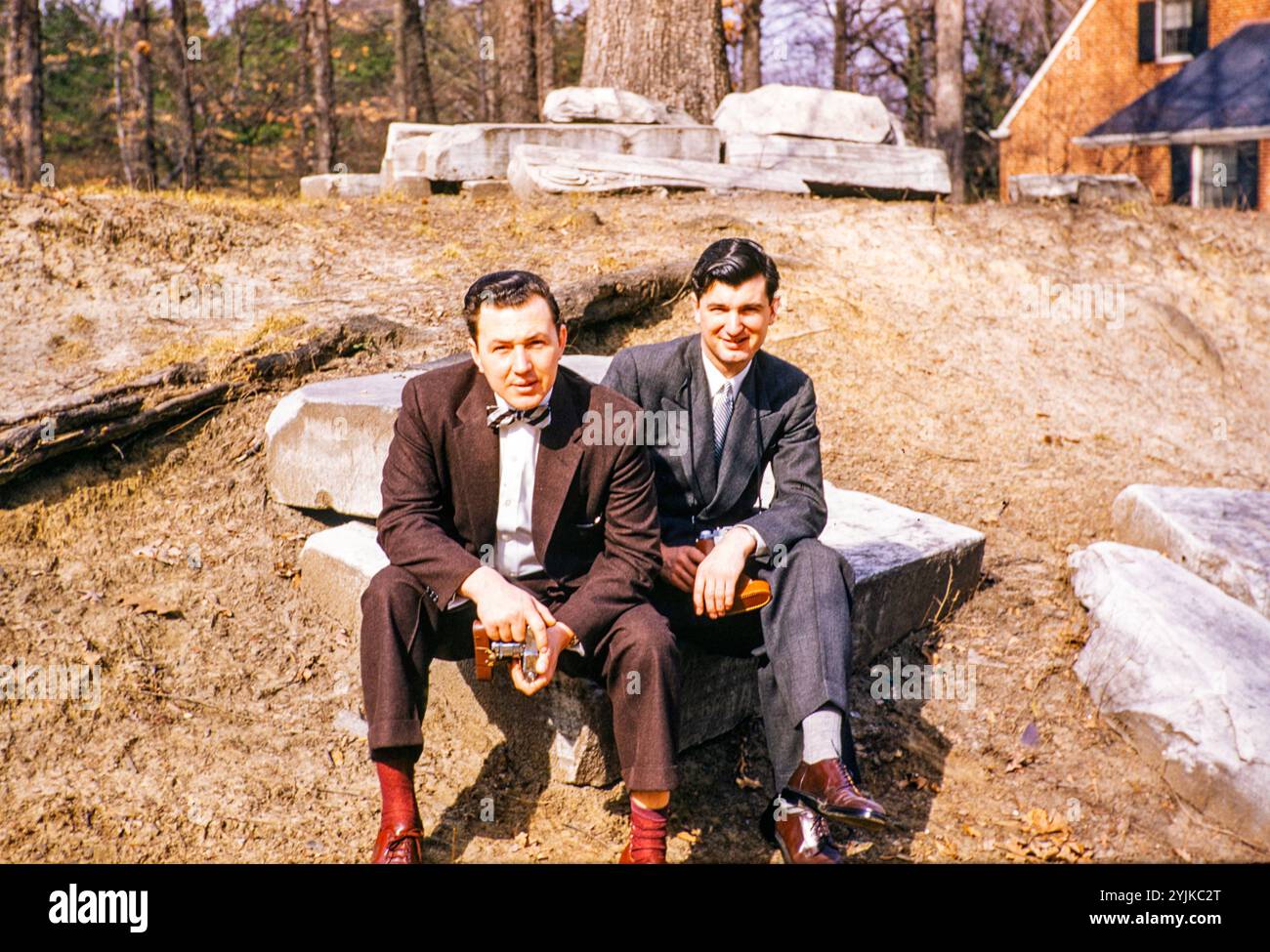 Two smartly dressed men sitting outside looking at camera, USA c 1953 ...