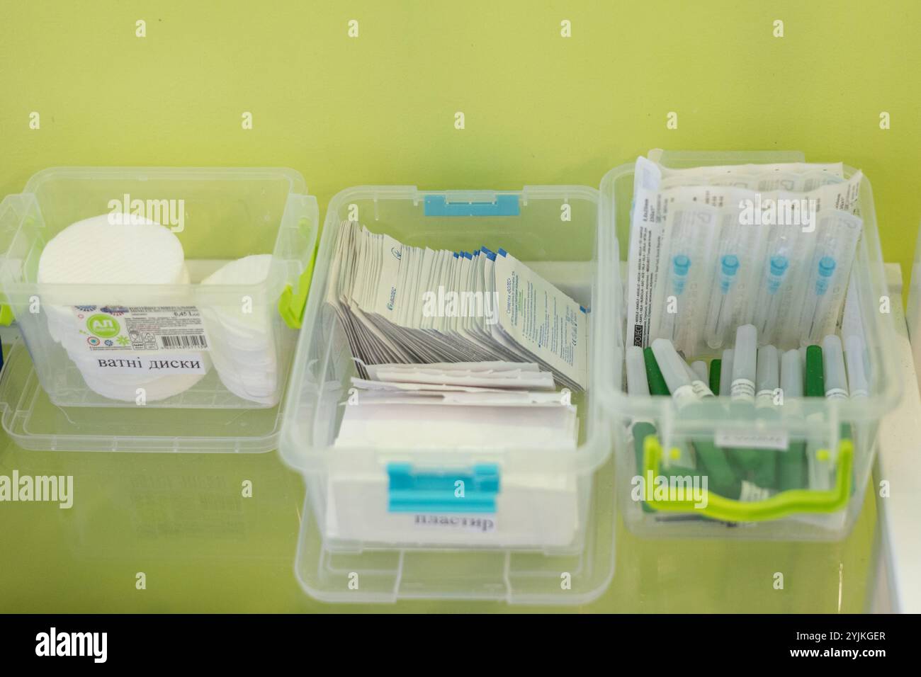 The image shows three plastic containers with medical supplies: cotton ...