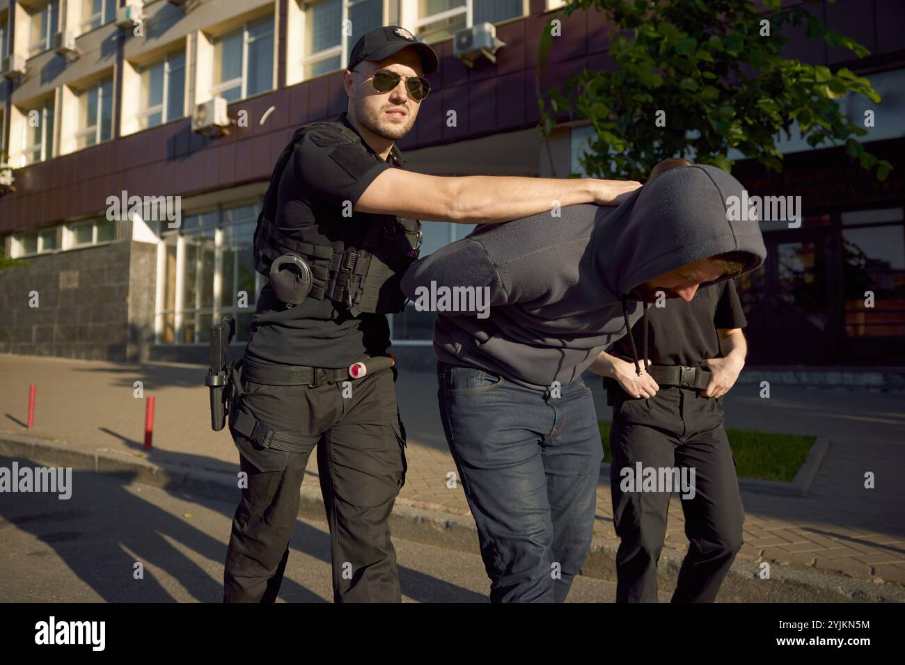 Two police officers providing arrest of criminal in act on city street ...