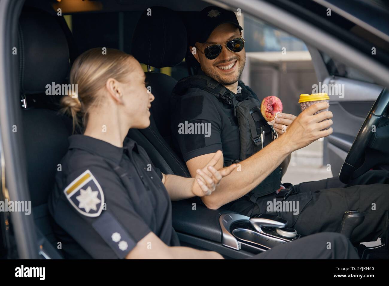 Patrol police officers diverse team sitting in car having coffee break ...