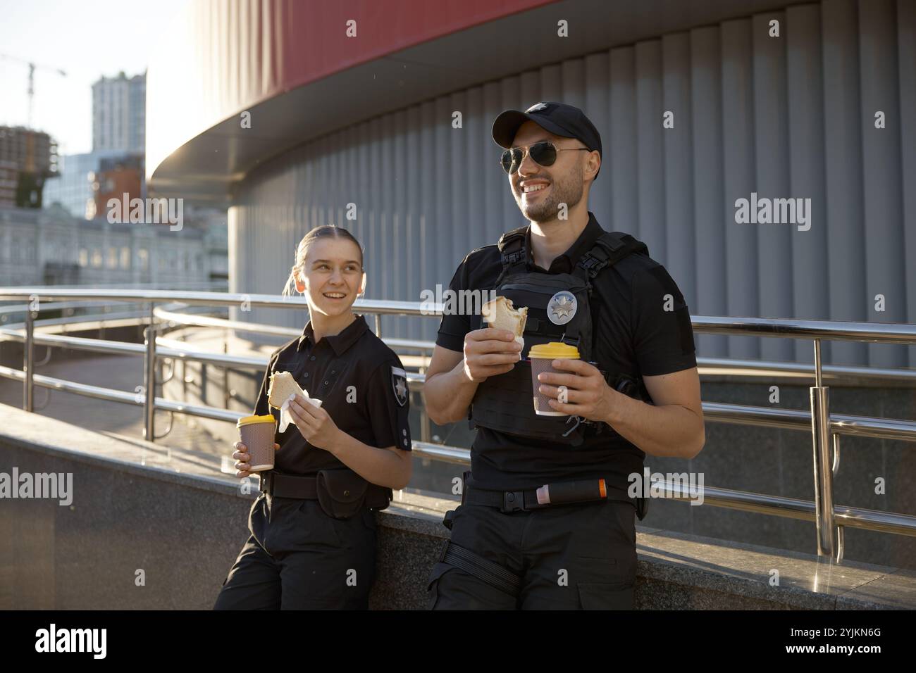 Male and female patrol police officers enjoying lunch break outdoor ...