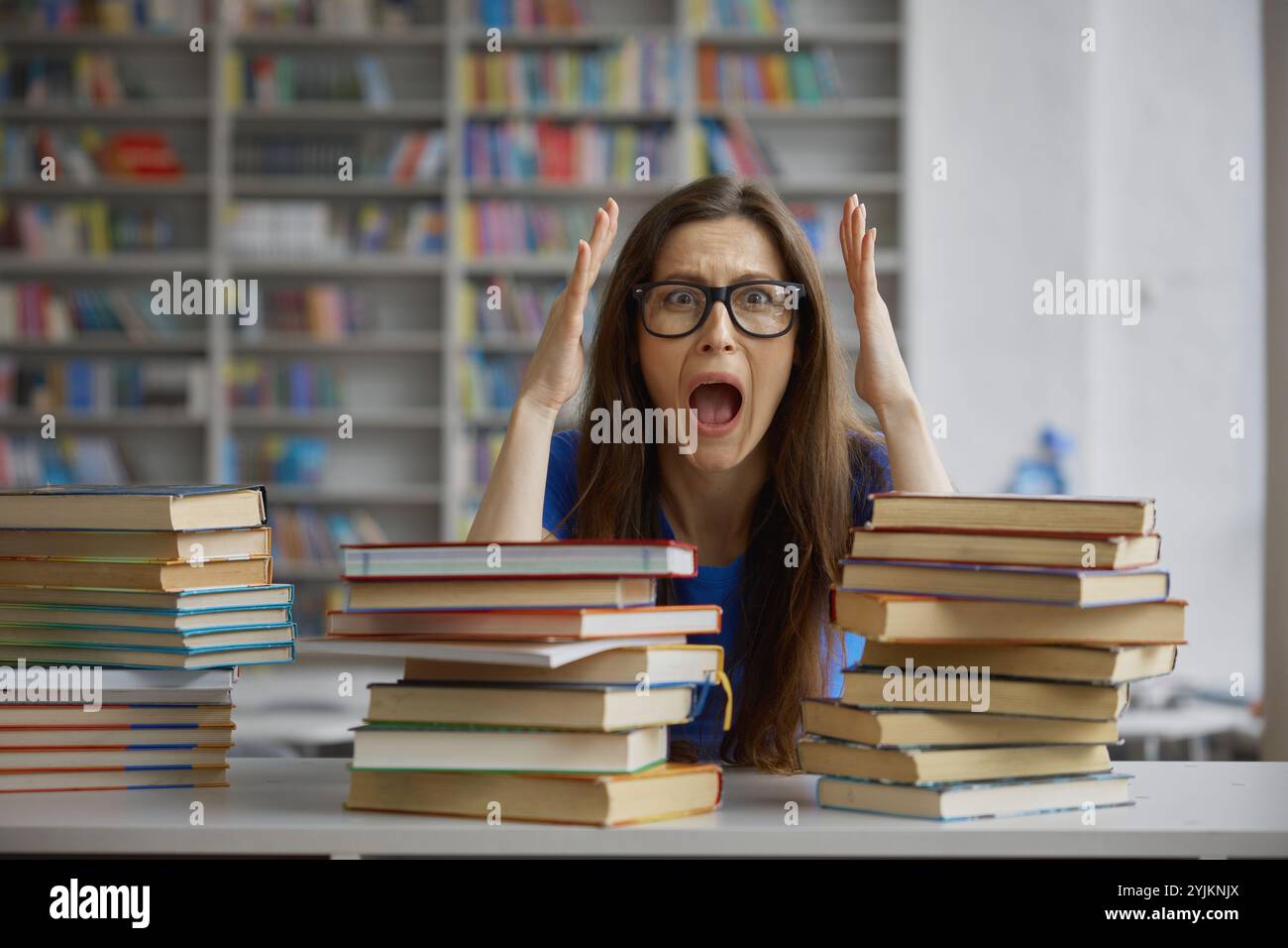 Upset woman screaming sitting front of huge stack of book in library ...