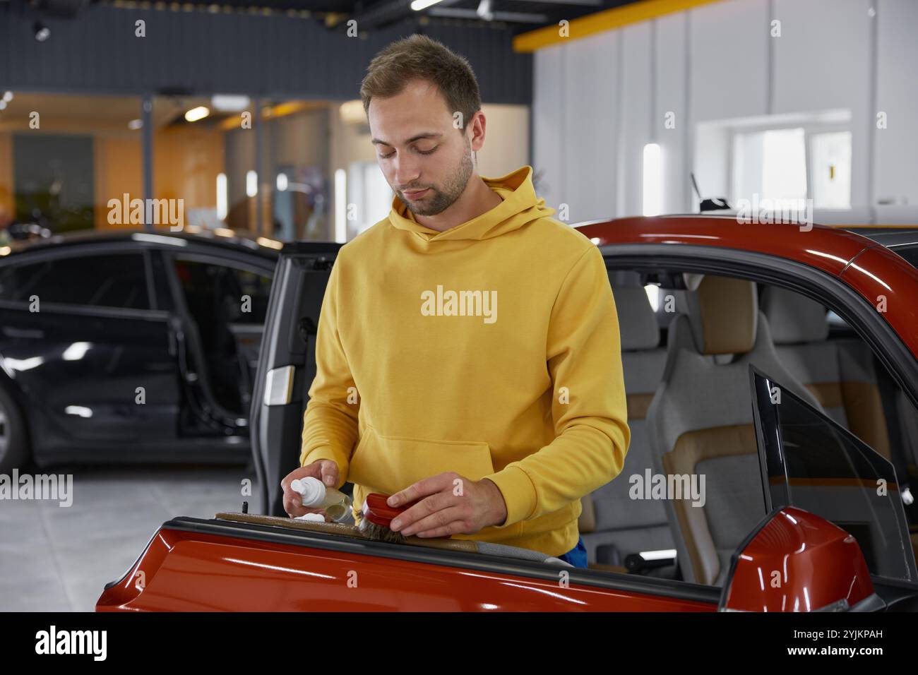 Man brushing leather parts of car door during auto detailing procedure ...
