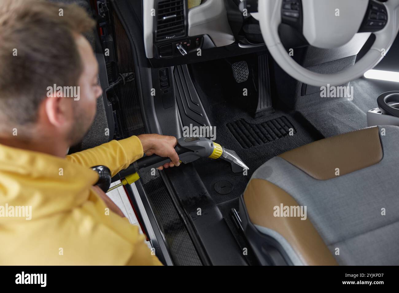 Car wash service worker vacuuming dust form back passenger seats Stock ...